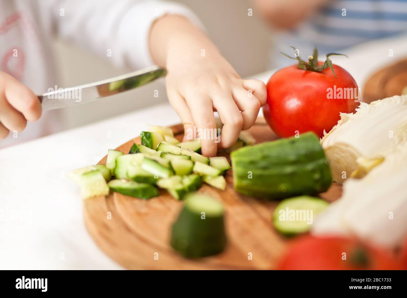 Happy children prepares vegetables for salad in home kitchen. Healthy ...