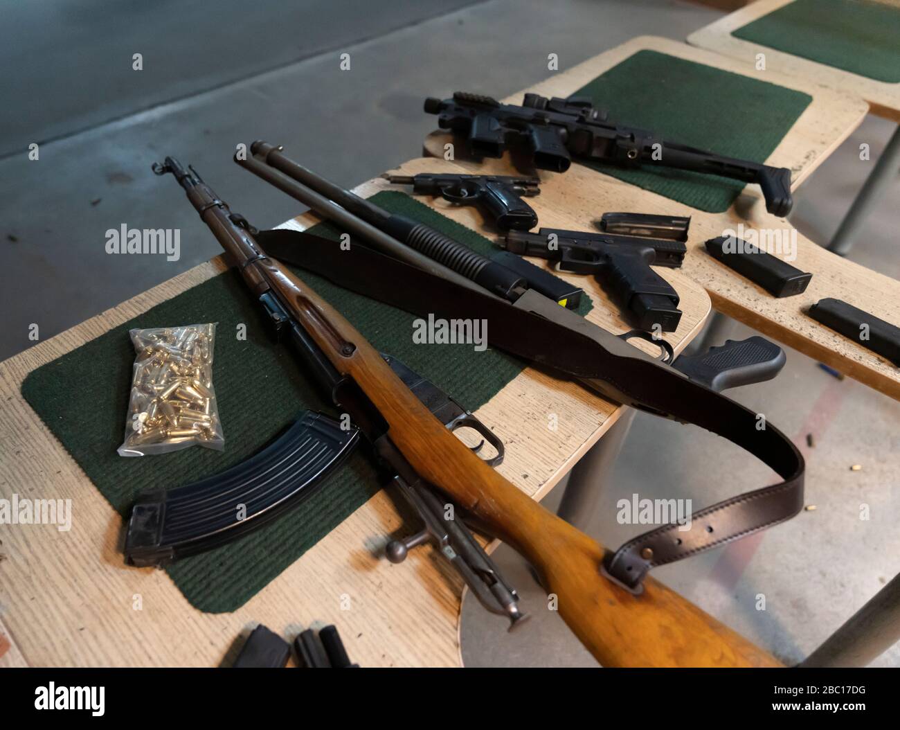 Guns on the table in shooting range Stock Photo - Alamy