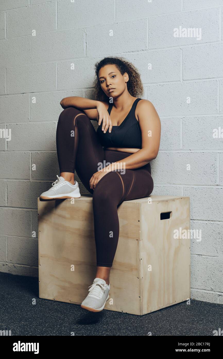Portrait of confident athletic young woman sitting on a box Stock Photo ...
