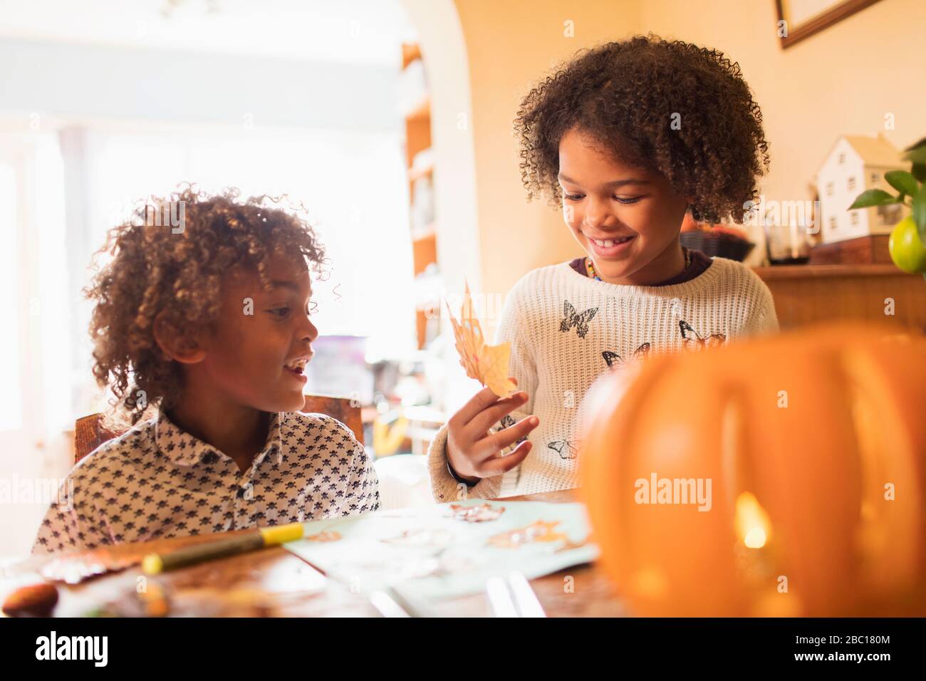 Brother and sister making autumn crafts at table Stock Photo - Alamy
