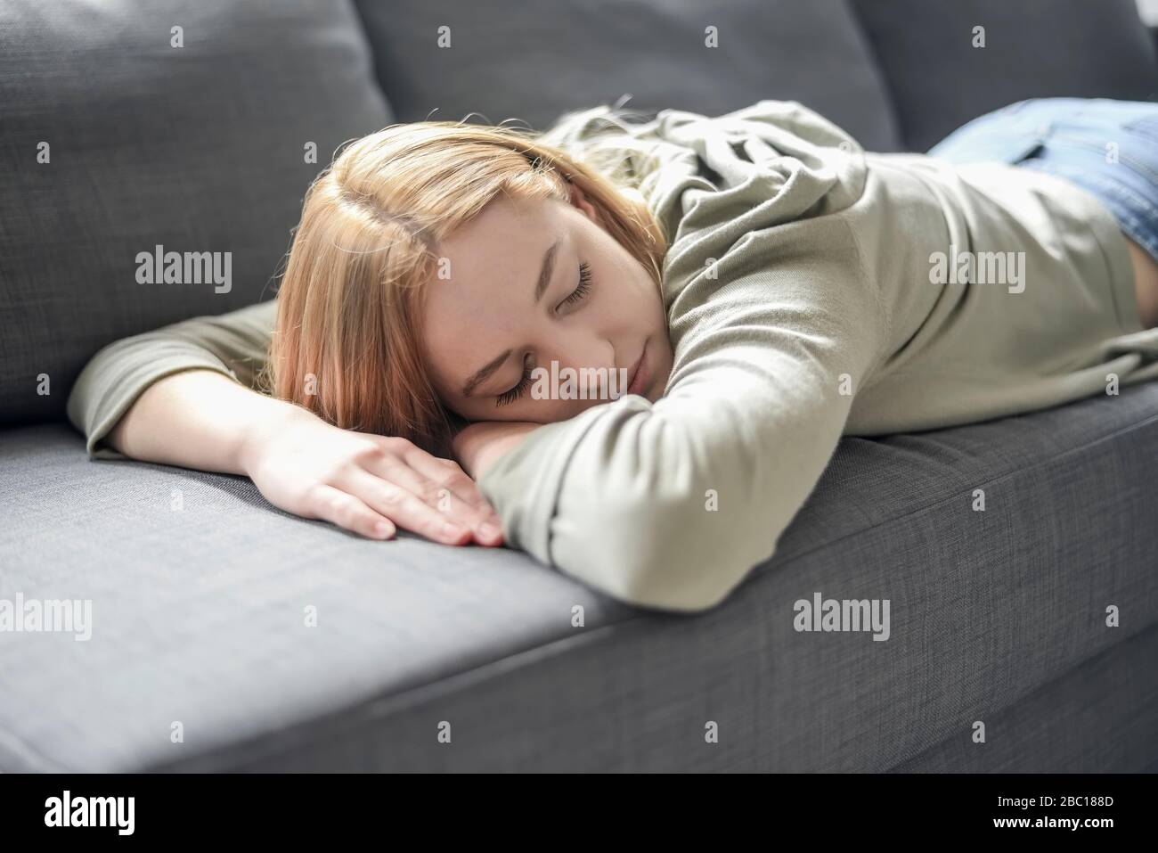 Portrait of blond young woman napping on the couch Stock Photo - Alamy