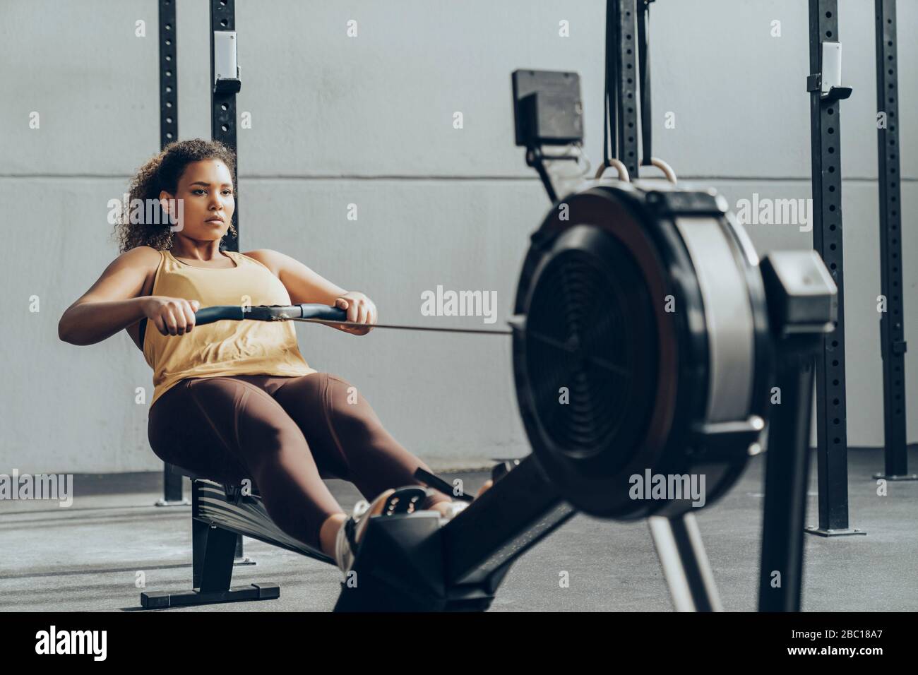 Young woman exercising in gym with rowing machine Stock Photo - Alamy