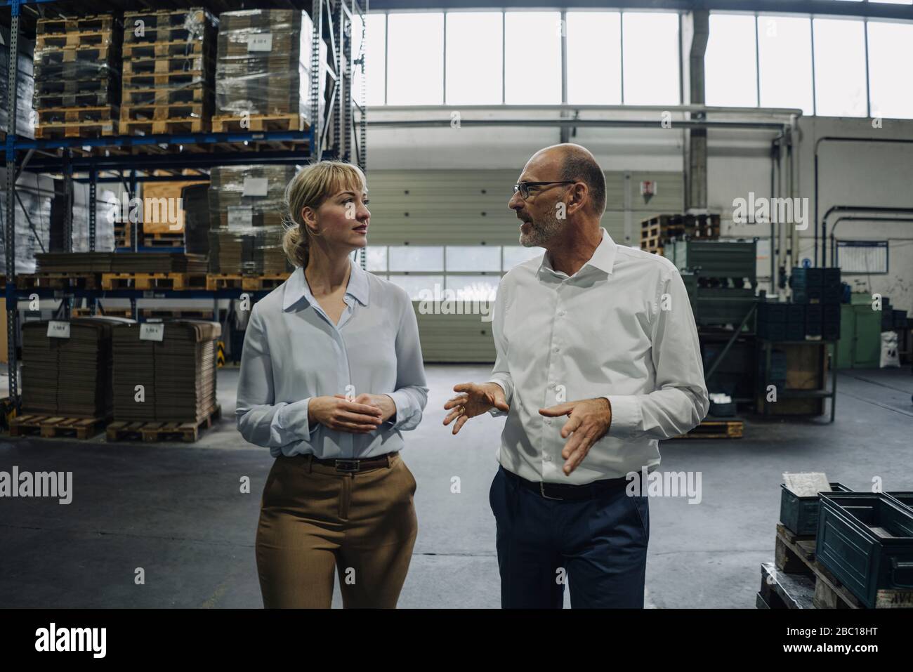 Man and woman walking and talking in a factory Stock Photo - Alamy