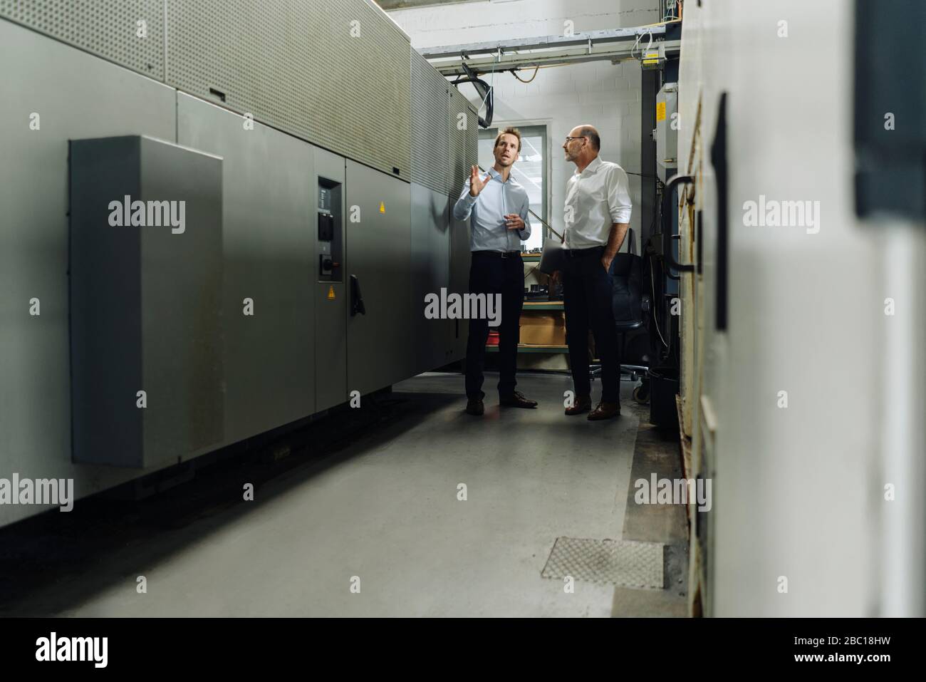 Two men talking in a factory Stock Photo - Alamy