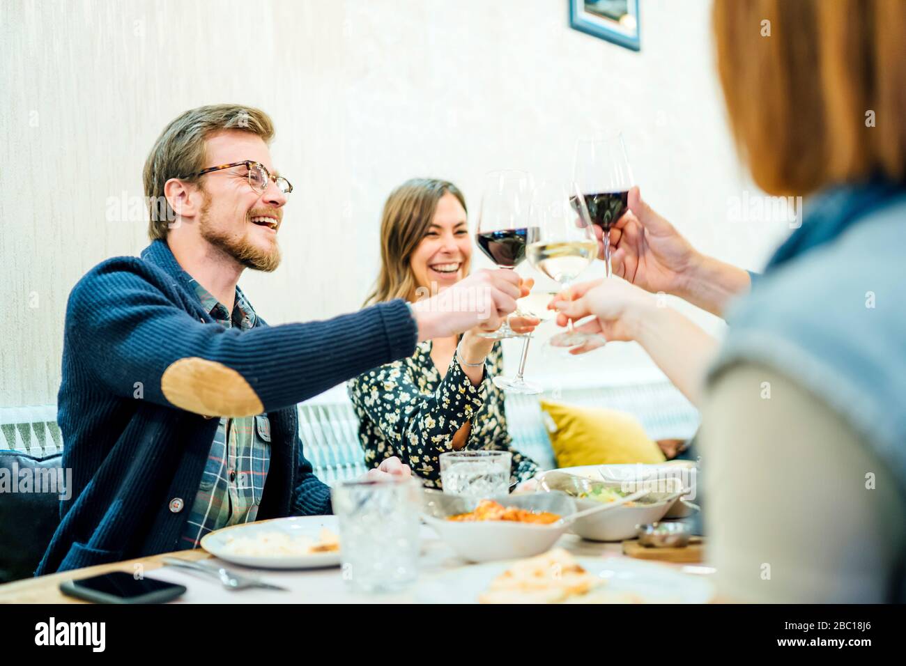 Friends dining in an Indian restaurant, toasting wine glasses Stock ...
