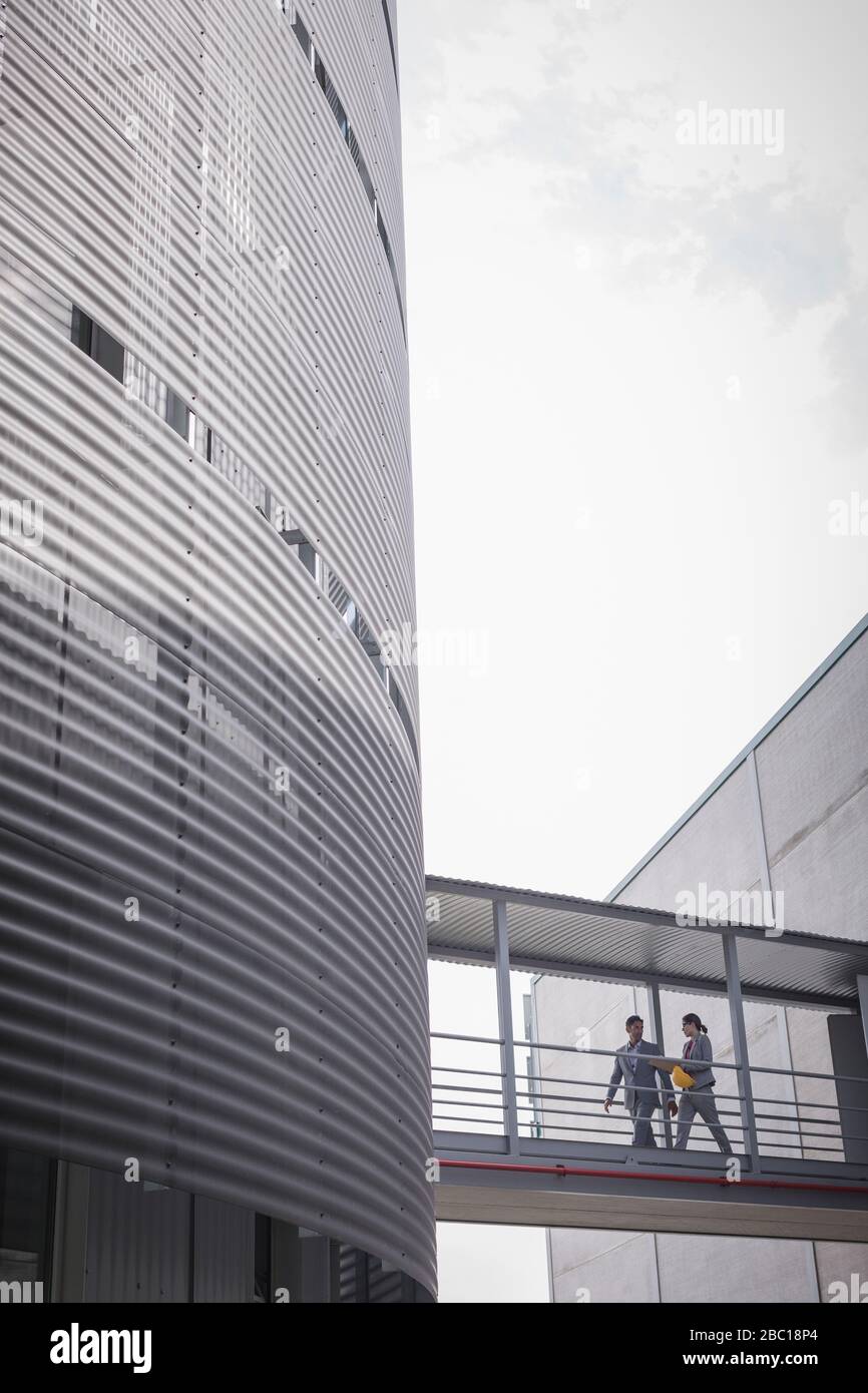 Supervisors walking on elevated walkway between factory buildings Stock ...