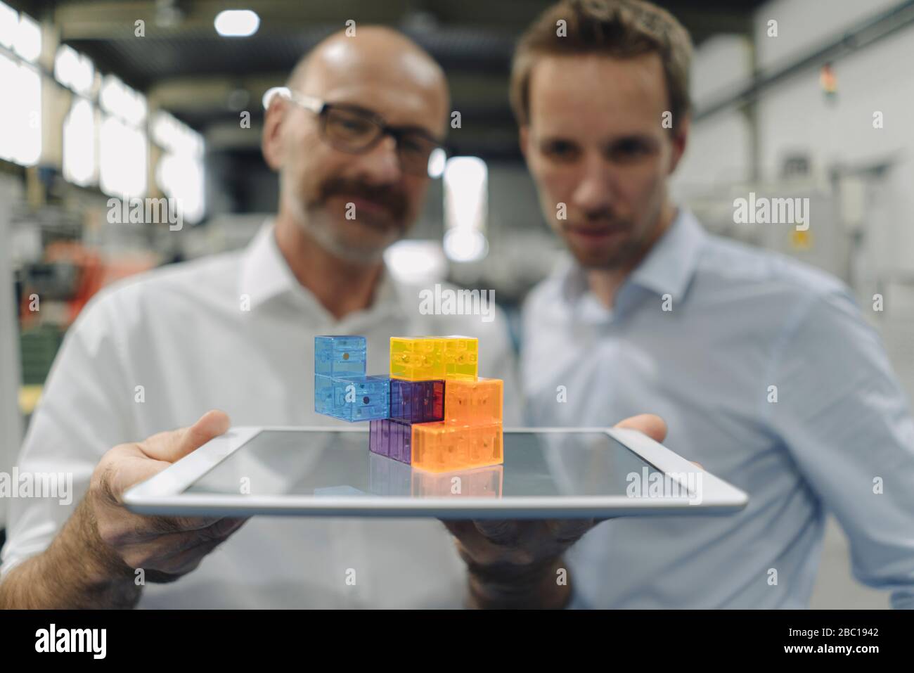 Two men examining workpiece on tablet in a factory Stock Photo - Alamy