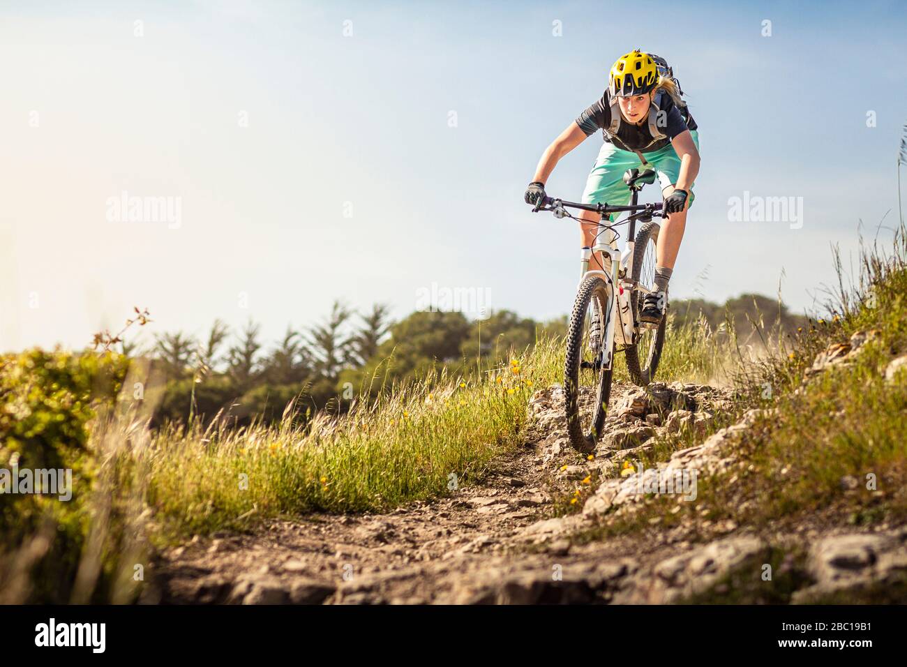 Woman on mountain bike riding down trail in front of blue sky, Santa ...