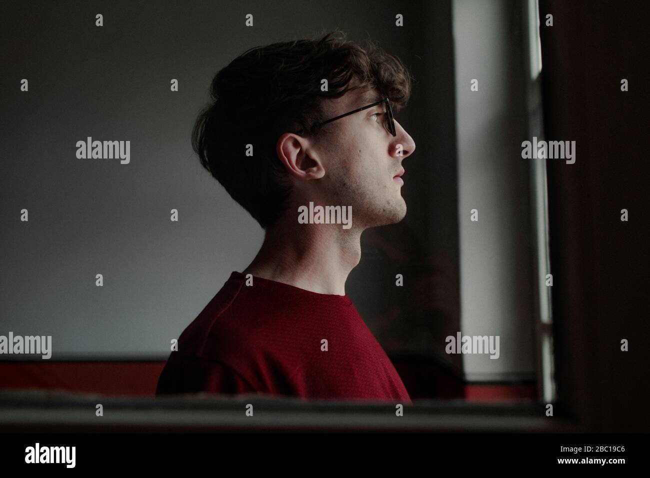 Profile of pensive young man looking out of window Stock Photo - Alamy