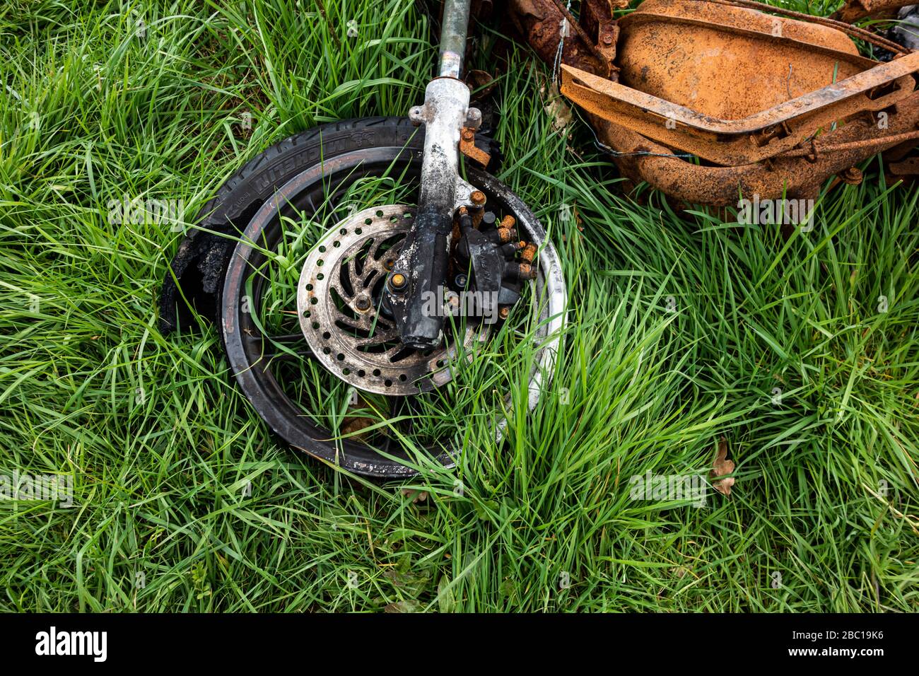 Burnt out motorcycle dumped in a park front wheel close-up Stock Photo ...