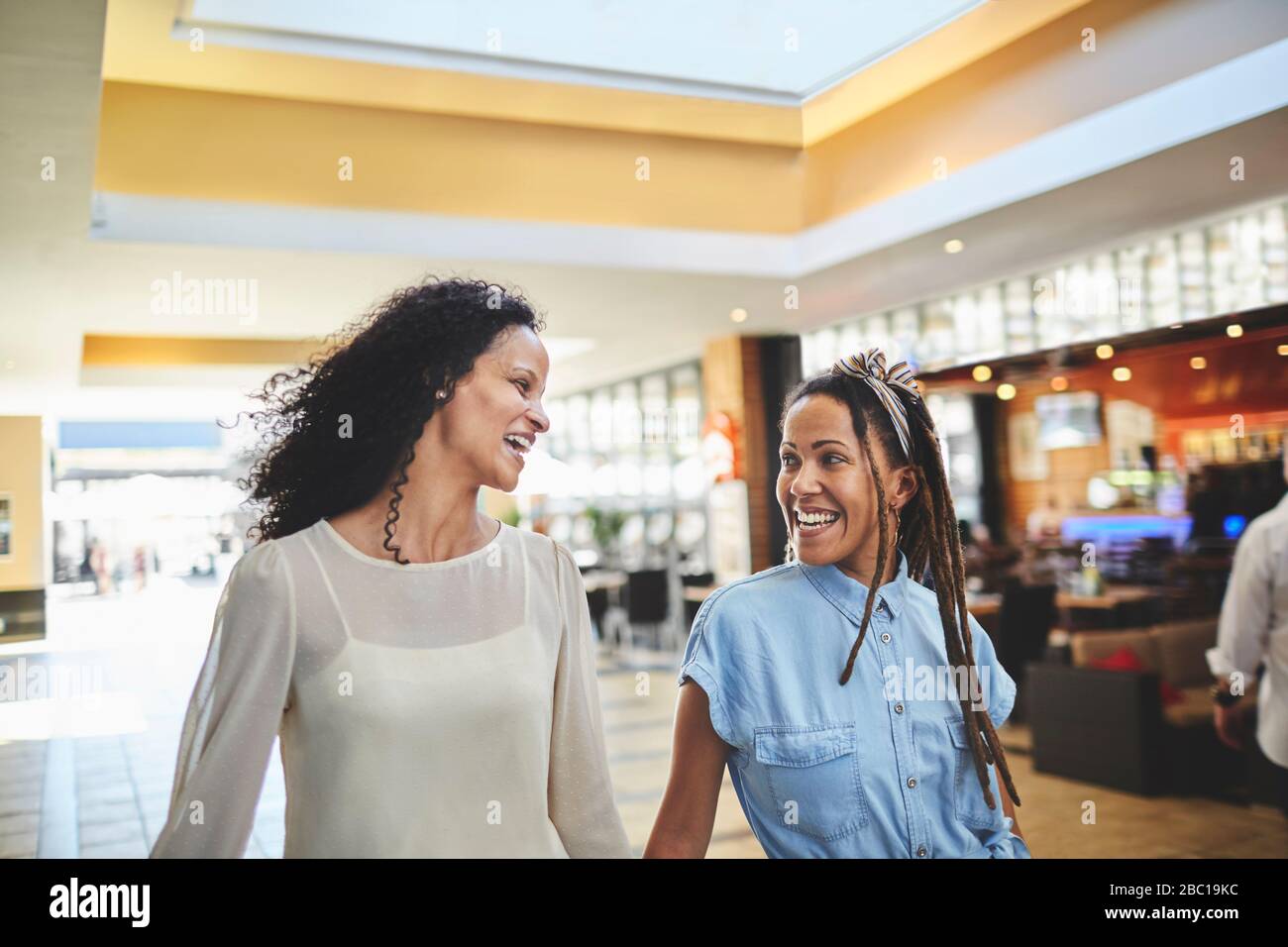 Happy women friends shopping in mall Stock Photo - Alamy