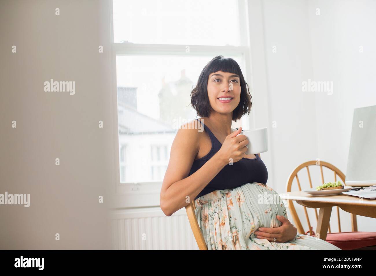 Beautiful pregnant woman drinking tea at dining table Stock Photo - Alamy