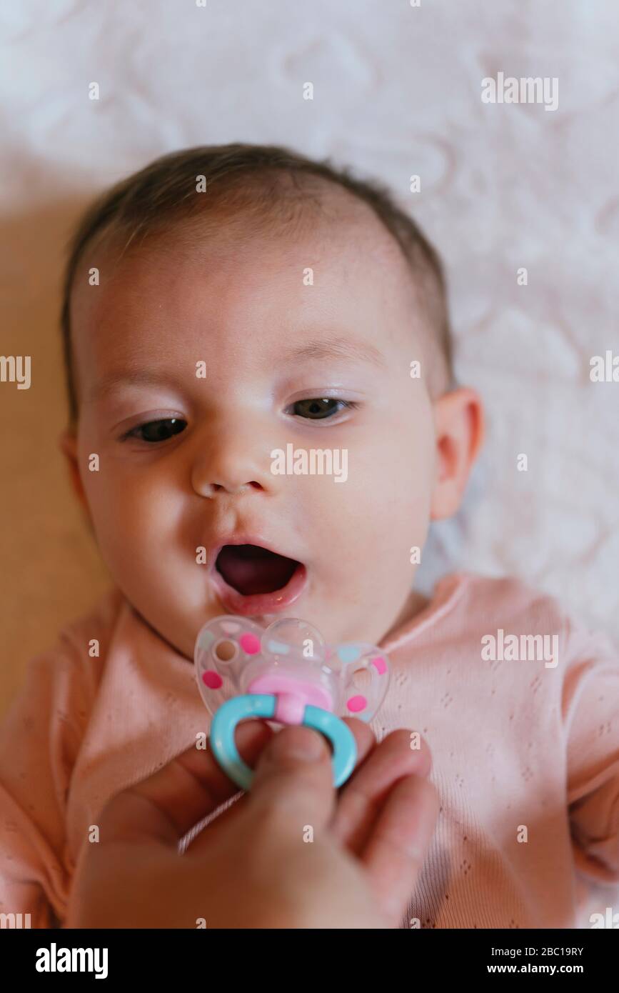 Mother's hand giving the pacifier to baby girl lying on bed Stock Photo ...