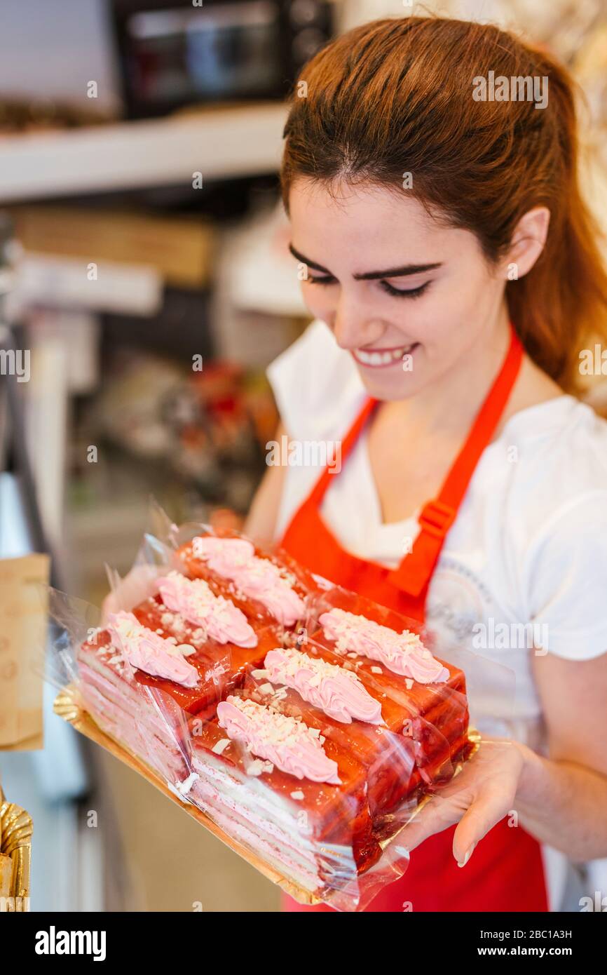 Young woman working in a bakery, showing cream cake Stock Photo - Alamy
