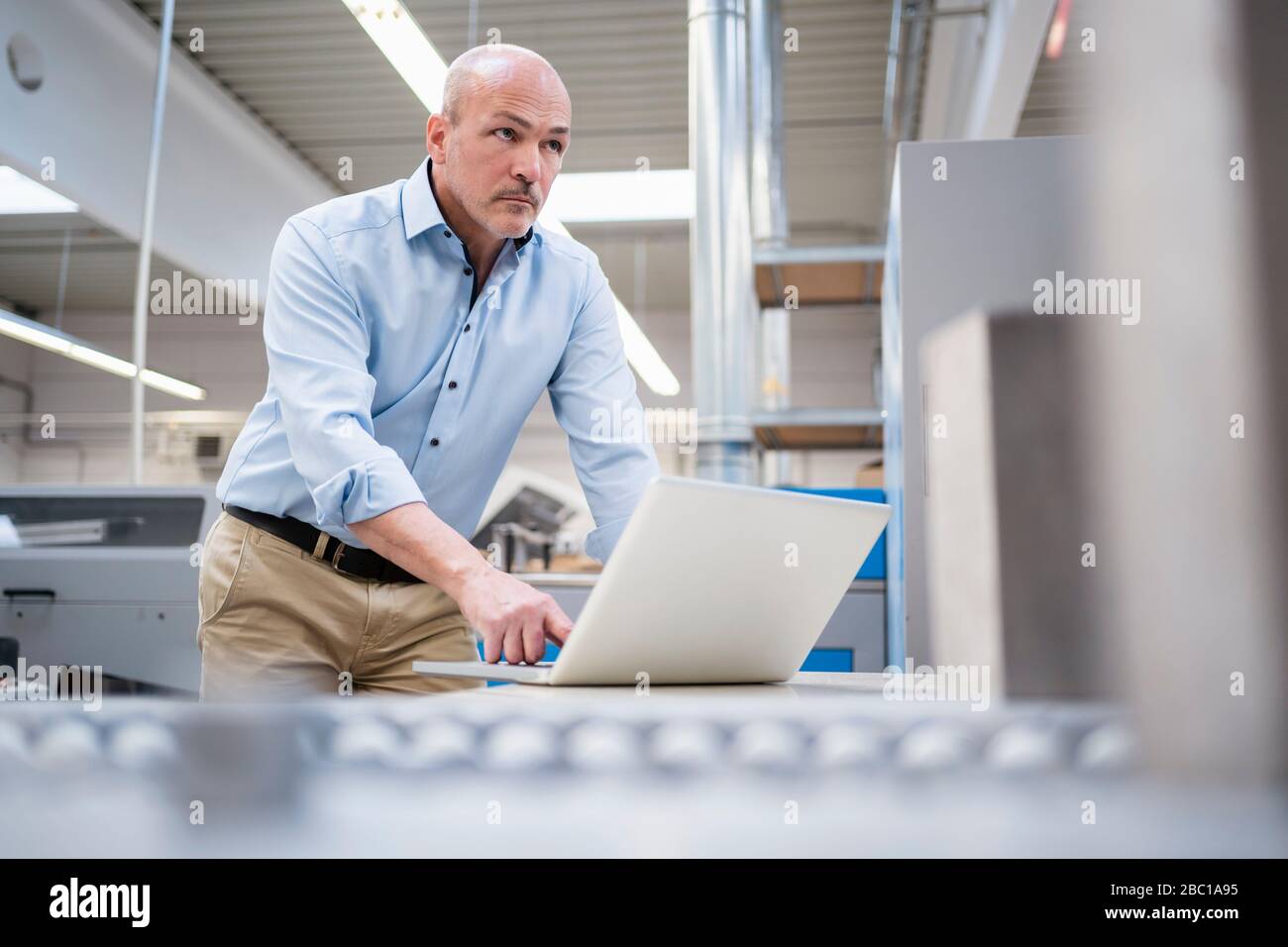 Businessman using laptop in a factory Stock Photo - Alamy