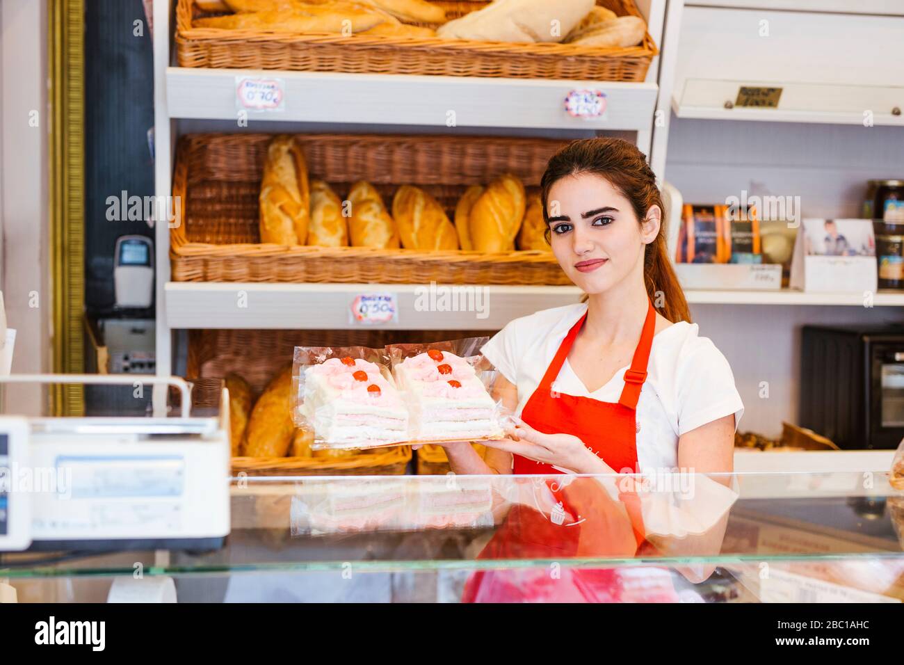 Young woman working in a bakery, showing cream cake Stock Photo - Alamy
