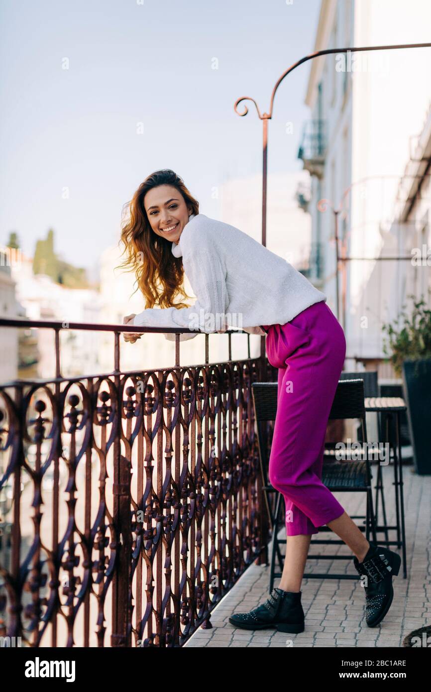 Portrait of happy young woman standing on balcony Stock Photo - Alamy