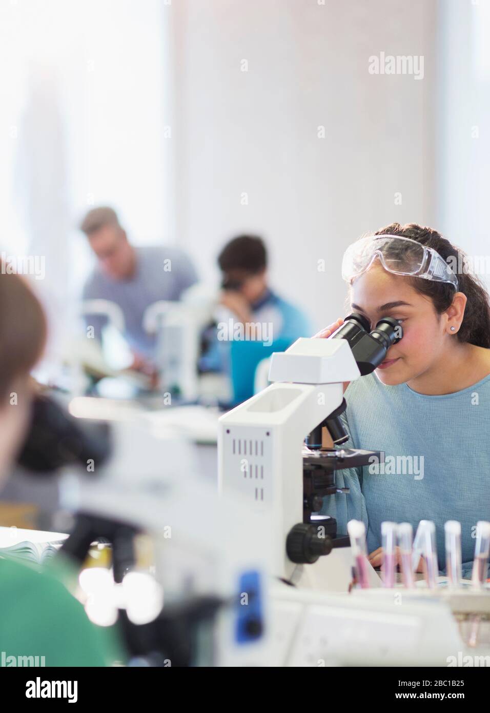 Girl student using microscope, conducting scientific experiment in ...