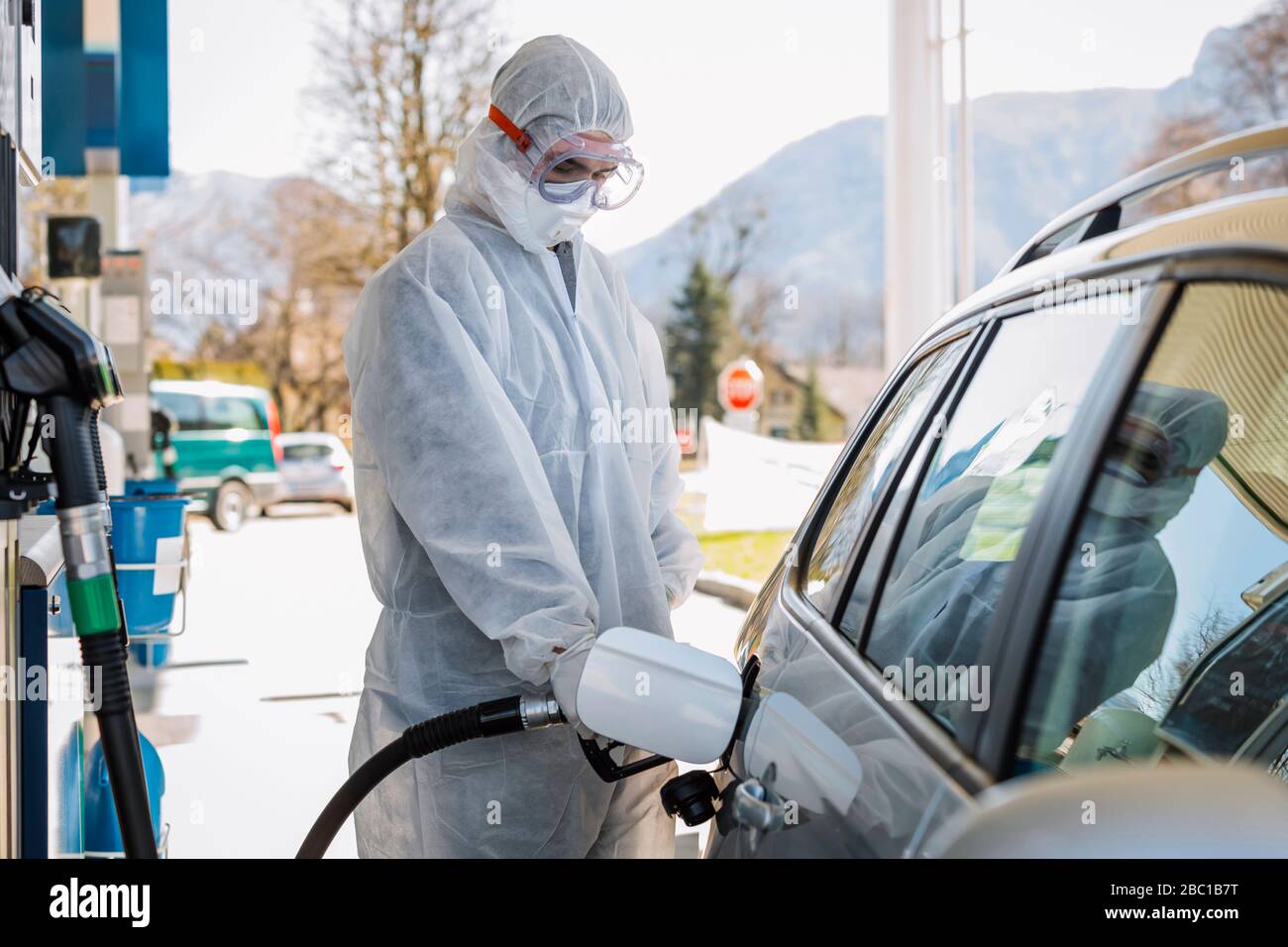 Man wearing protective clothing refueling car at gas station Stock ...