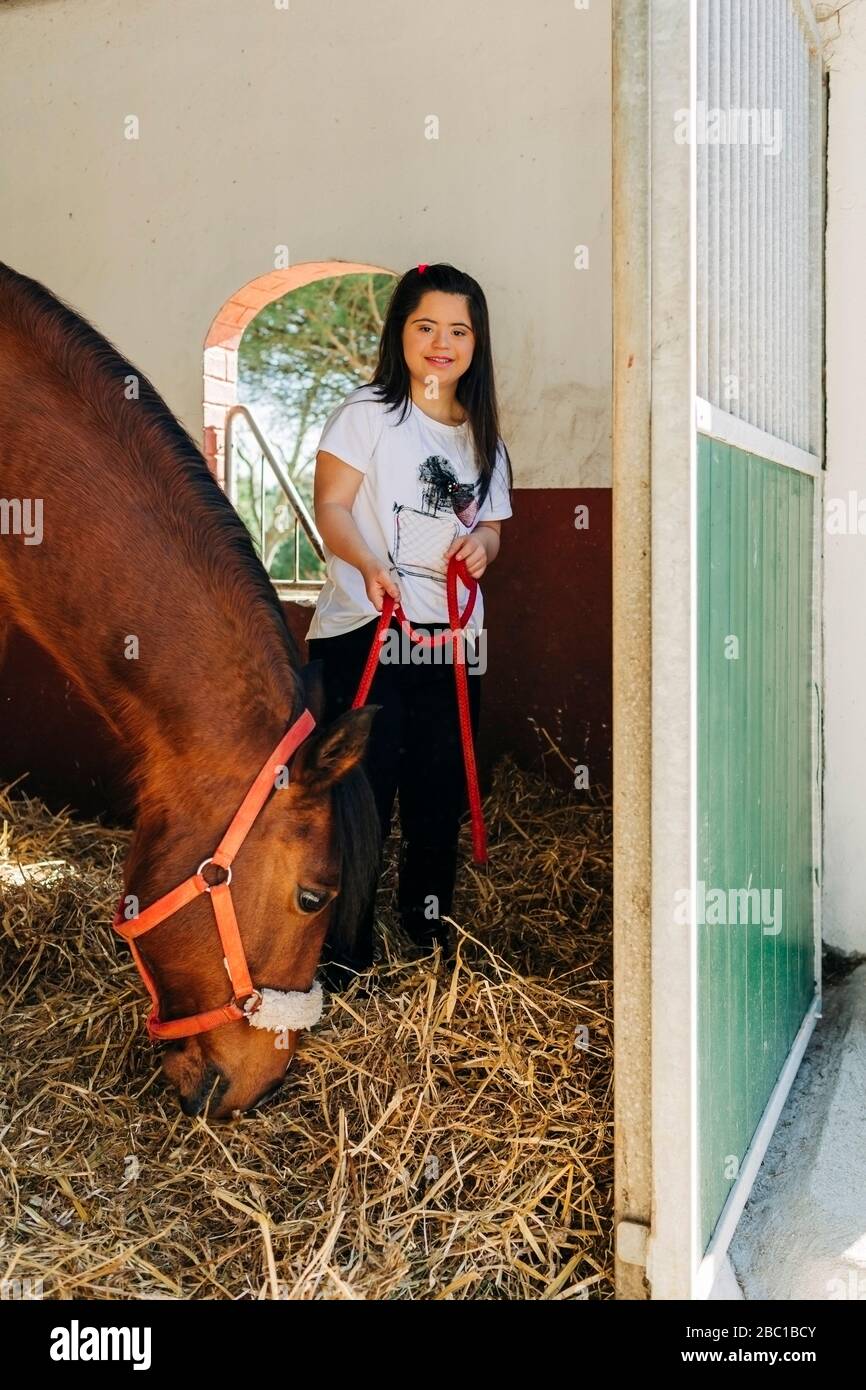 Teenager with down syndrome taking care of horse and preparing horse to ...