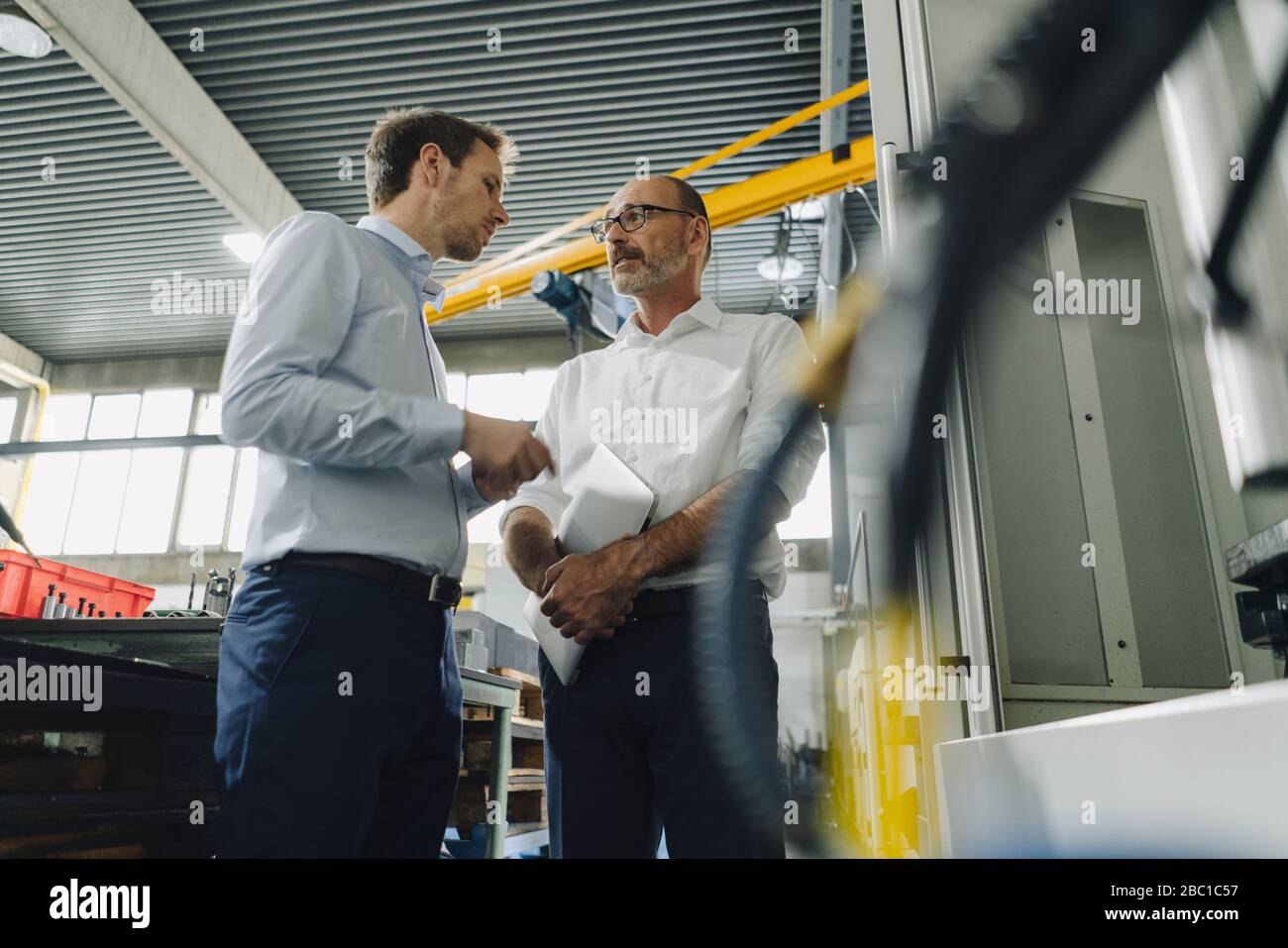 Two men talking in a factory Stock Photo - Alamy
