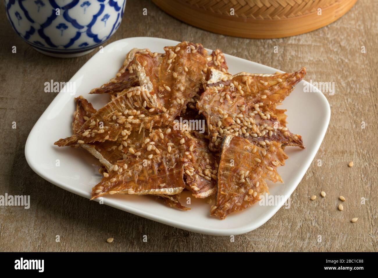Dish with Thai deep fried yellowtail fish bones with sesame seed close ...