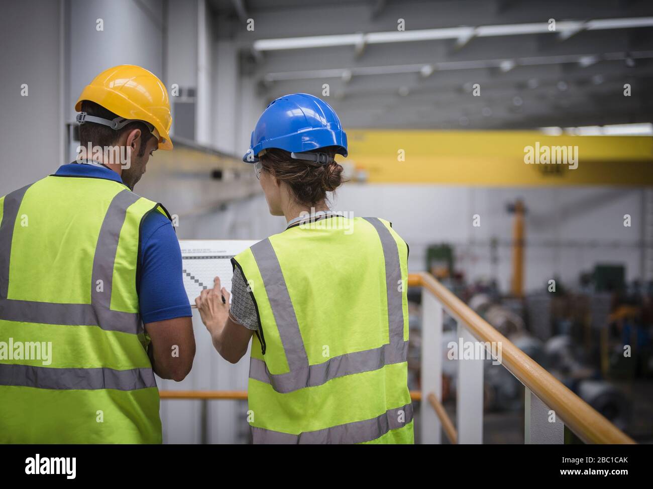 Supervisors discussing paperwork on platform in factory Stock Photo - Alamy