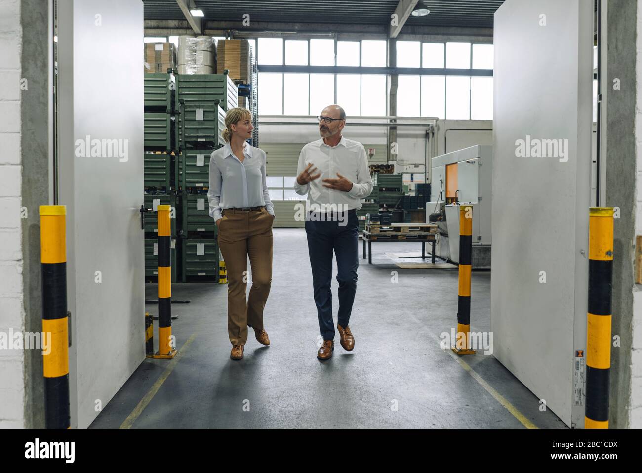 Man and woman walking and talking in a factory Stock Photo - Alamy