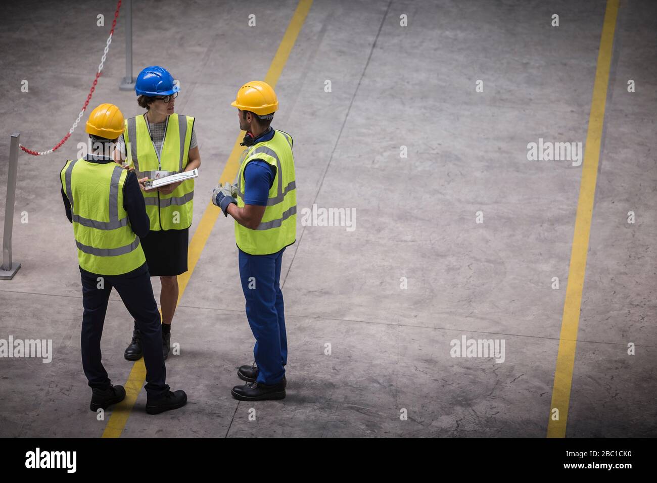 Supervisor and workers with clipboard talking in factory Stock Photo ...