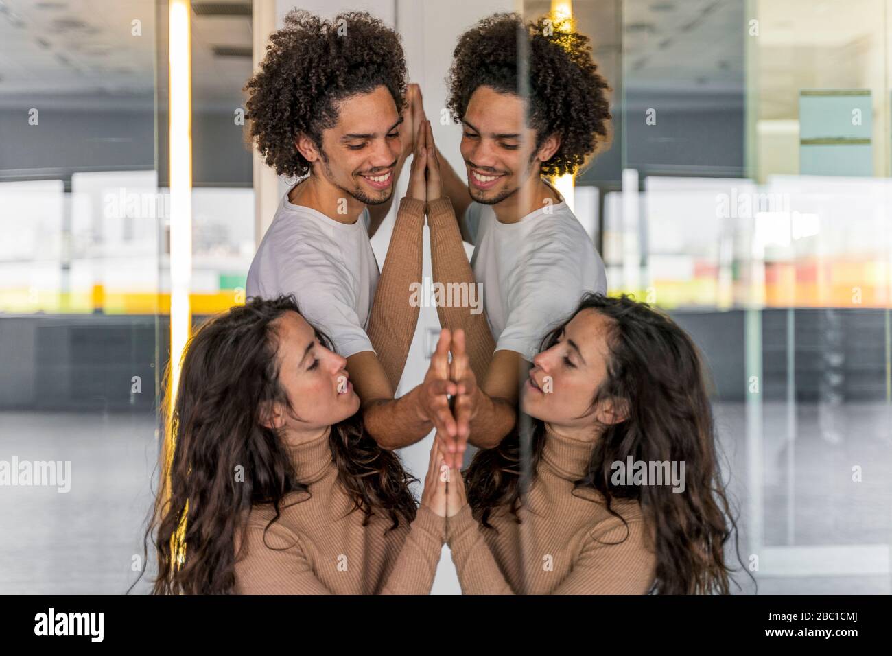 Couple touching mirror images of themselves on a glasspane Stock Photo ...