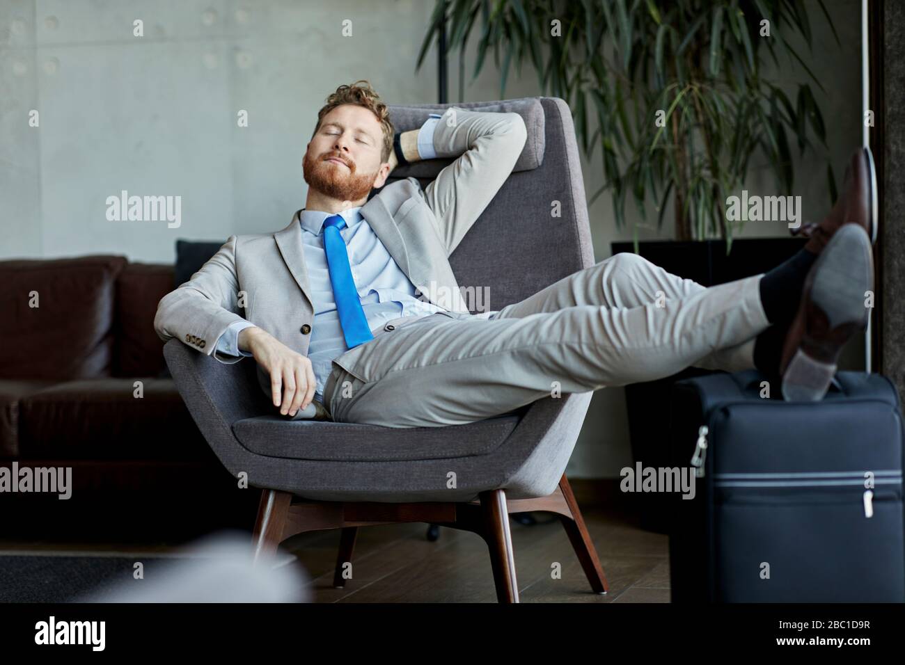 Businessman napping in hotel lobby Stock Photo - Alamy