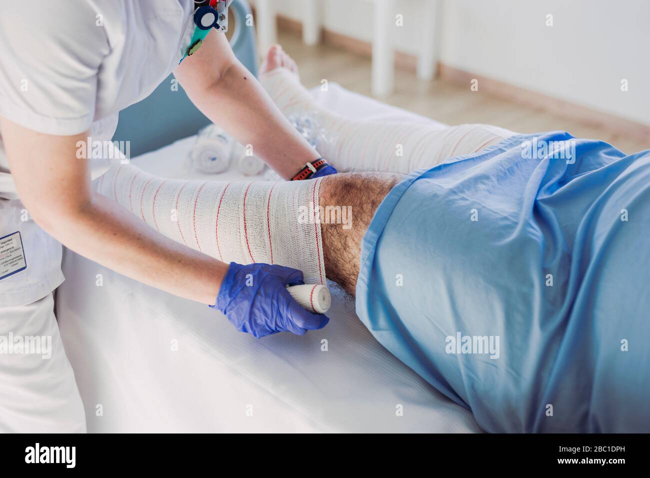 Nurse wrapping bandage around patient's leg in hospital bed Stock Photo ...
