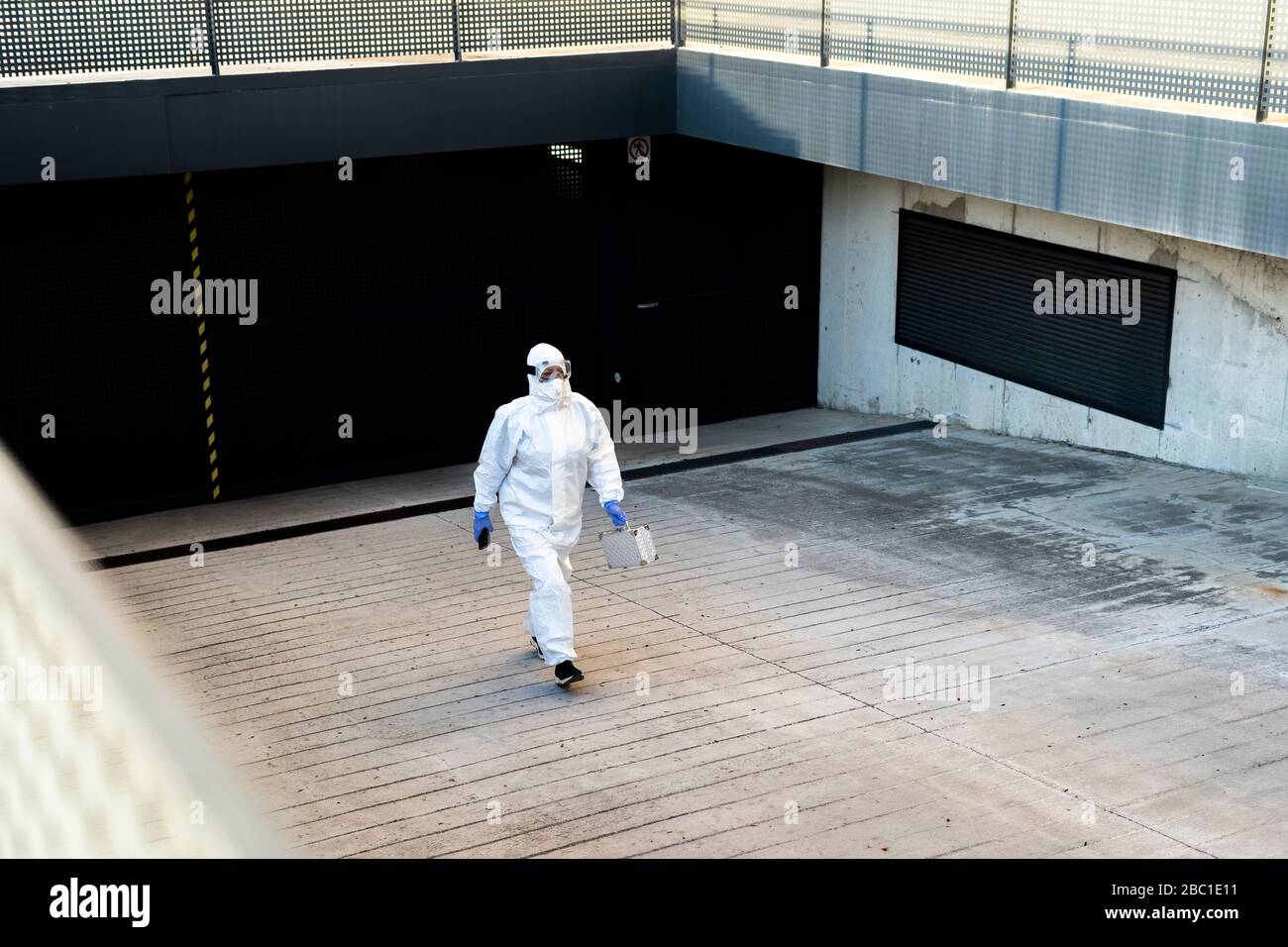 Female scientist wearing protective suit and mask and walking at a ...