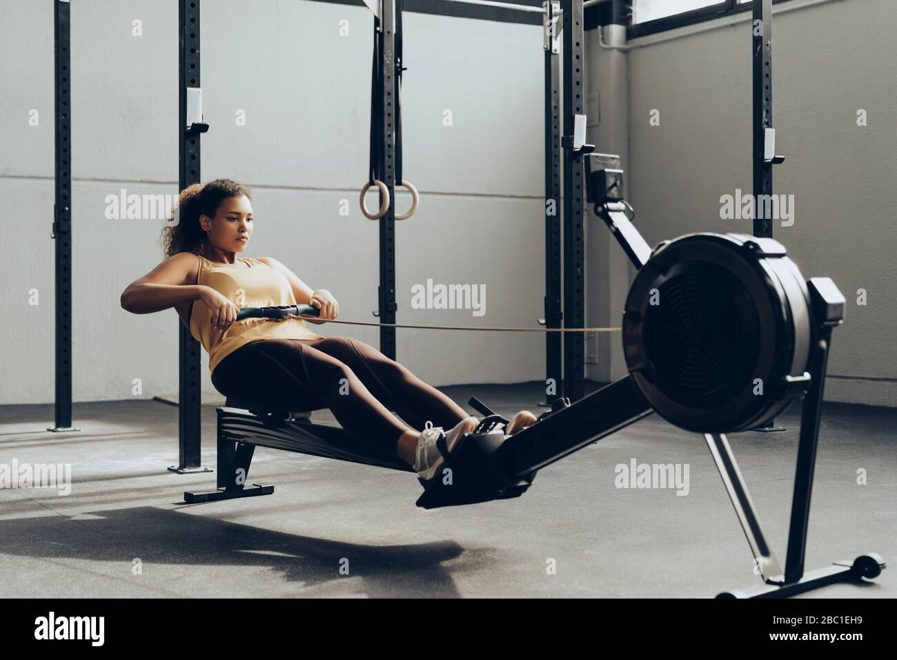 Young woman exercising in gym with rowing machine Stock Photo - Alamy
