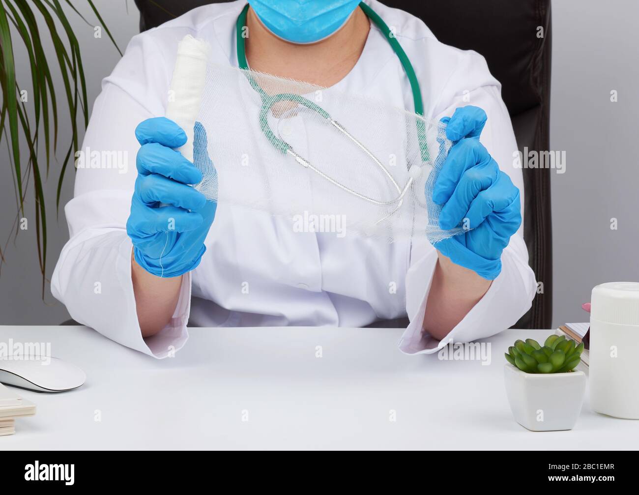 medic woman in white coat and mask holds a twisted gauze bandage for ...