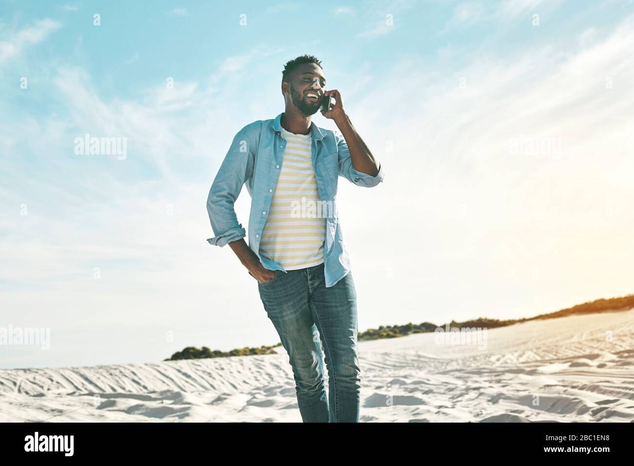 Young man talking on cell phone on sunny beach Stock Photo - Alamy