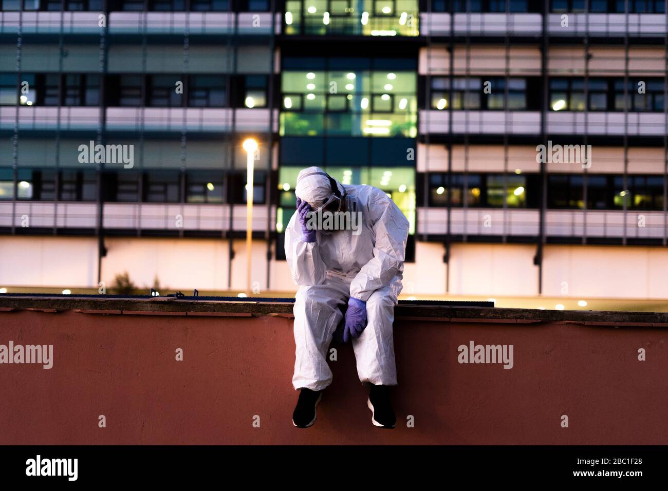 Female scientist wearing protective suit and mask sitting in front of a ...