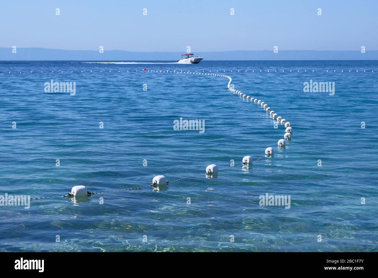 Plastic white buoy in blue sea. Float holds the cable at blue water ...