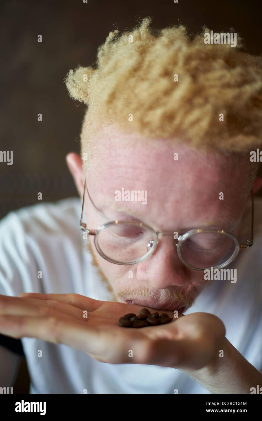 Albino man in a cafeteria smelling coffee beans in hand Stock Photo - Alamy