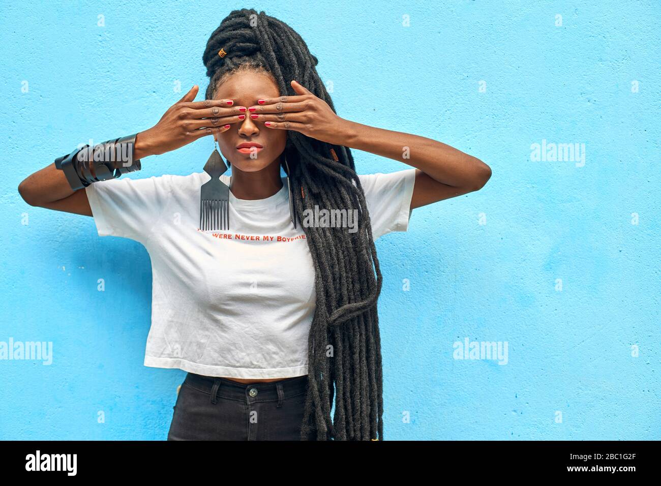Portrait of woman with long dreadlocks covering her eyes in front of ...