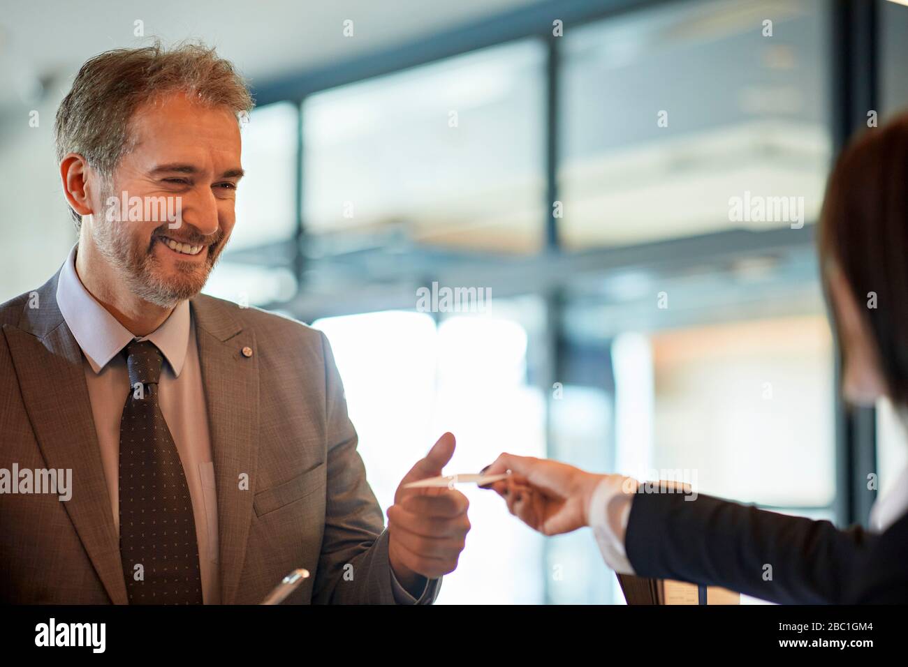 Portrait of smiling businessman checking in at hotel reception Stock ...