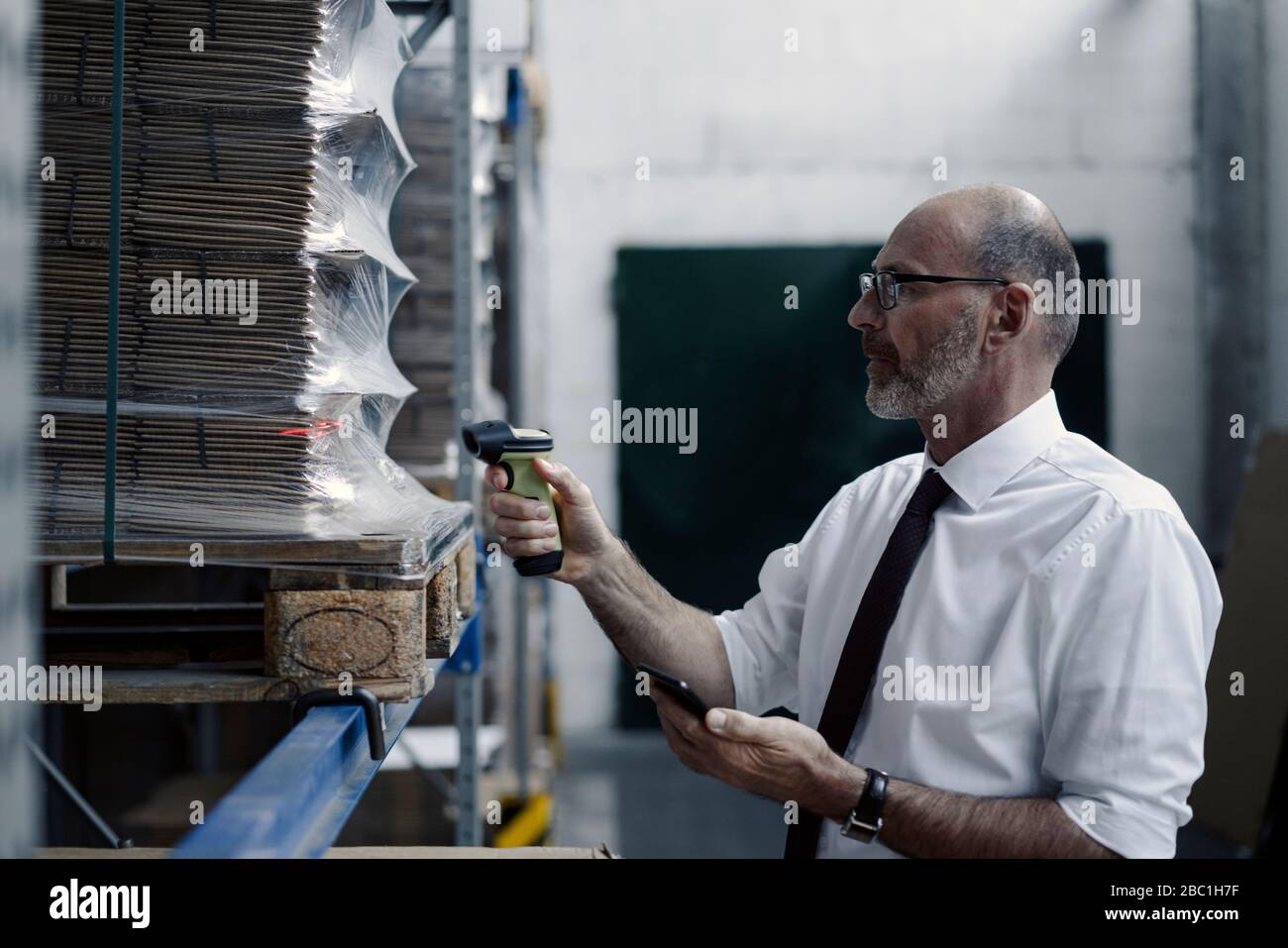 Man with smartphone and scanner in factory warehouse Stock Photo - Alamy
