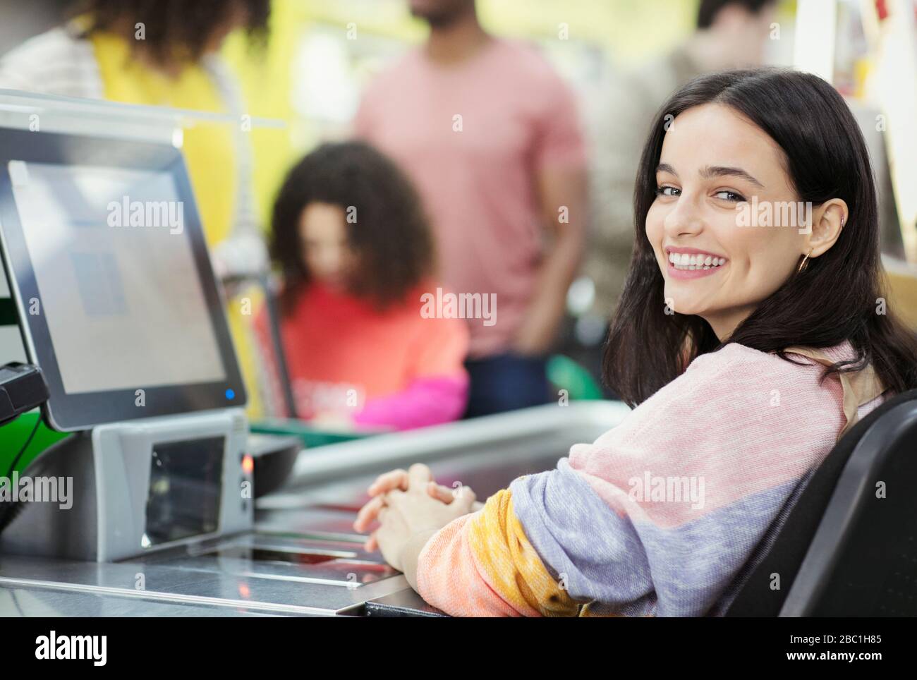 Portrait smiling, confident female cashier working at supermarket ...