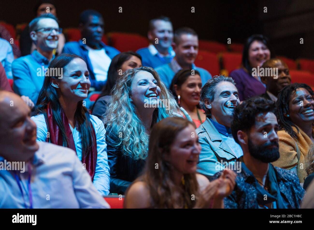 Smiling, enthusiastic audience in dark auditorium Stock Photo - Alamy