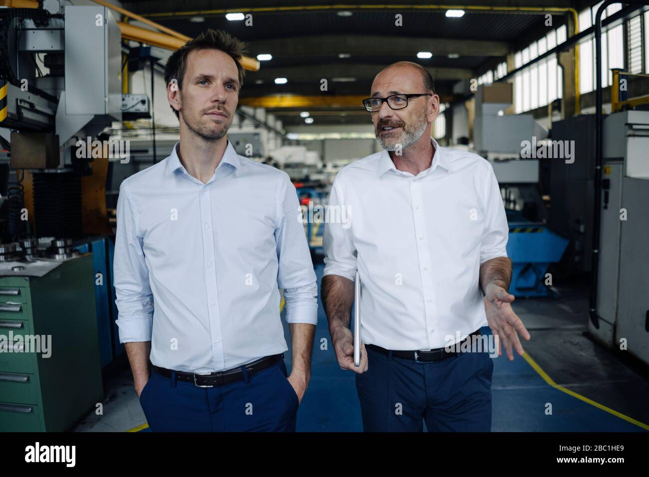 Two men talking in a factory Stock Photo - Alamy