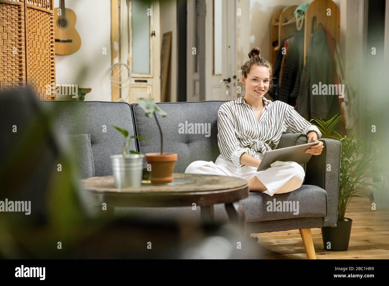 Young woman sitting at home on couch, using digital tablet Stock Photo ...