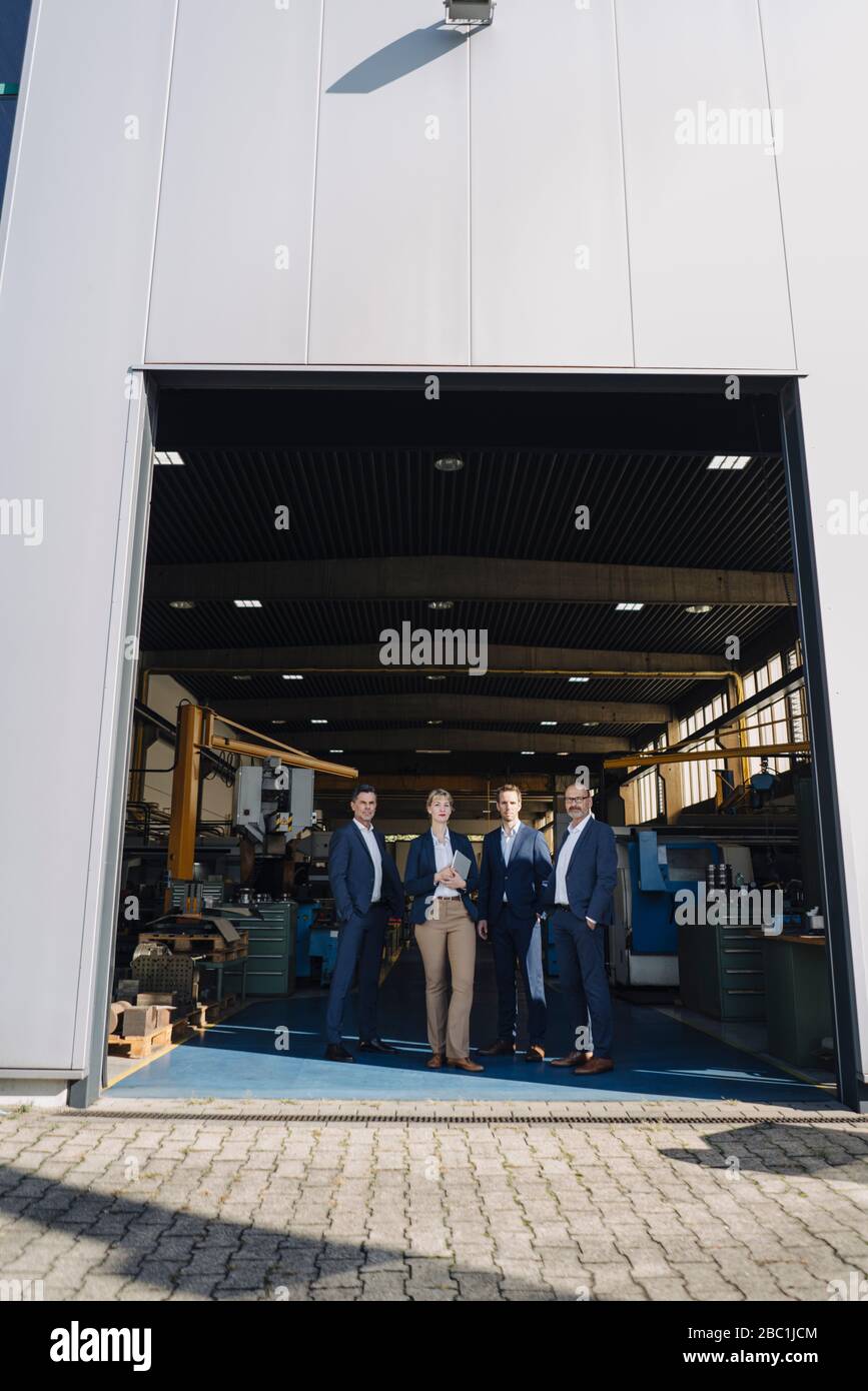 Portrait of confident business team standing at factory gate Stock ...