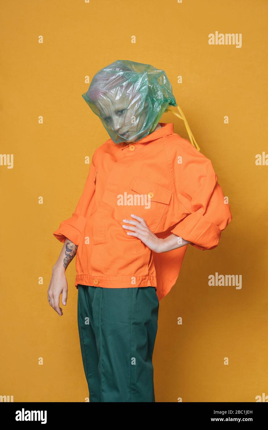 Portrait of young woman wearing orange jacket in front of yellow ...
