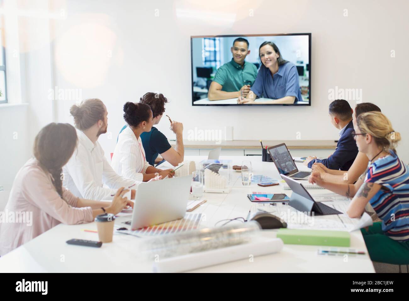 Designers video conferencing with colleagues in conference room meeting ...