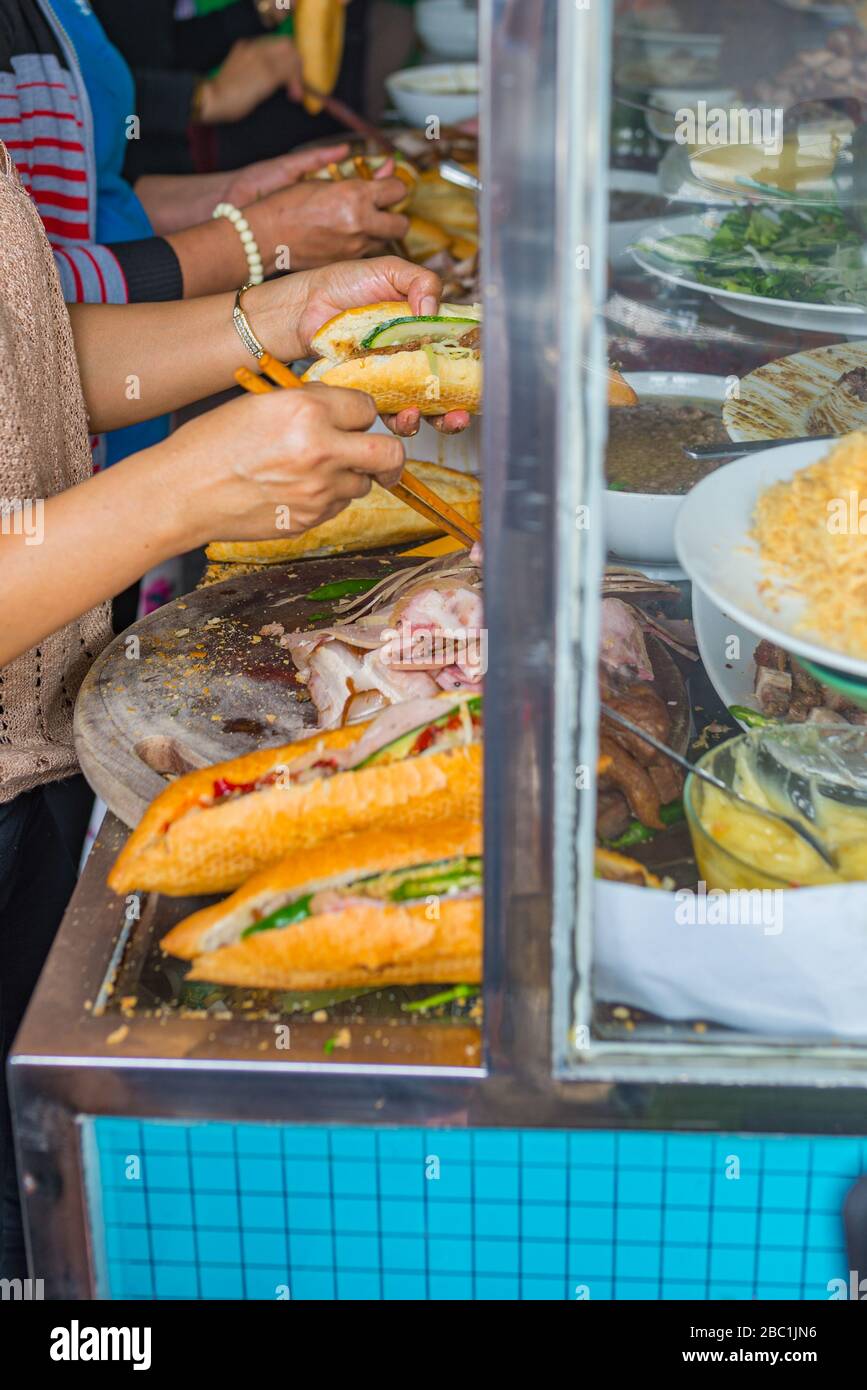 Vertical photo of women's hands making Banh Mi- Vietnamese sandwich ...